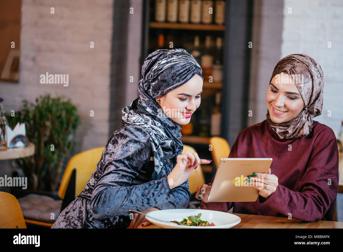 Two Muslim women in cafe, shop online using electronic tablet Stock ...
