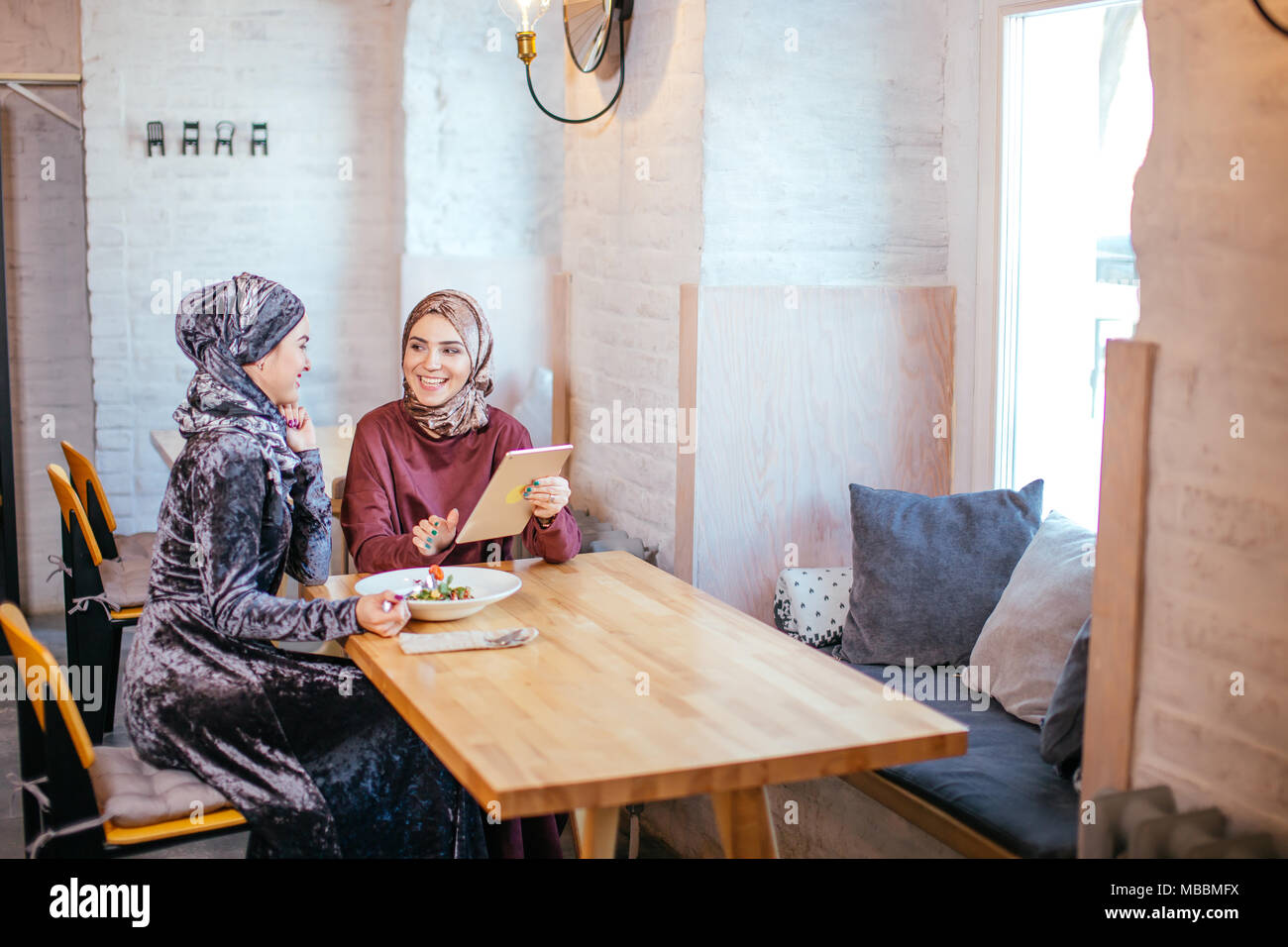 Two Muslim women in cafe, shop online using electronic tablet Stock ...