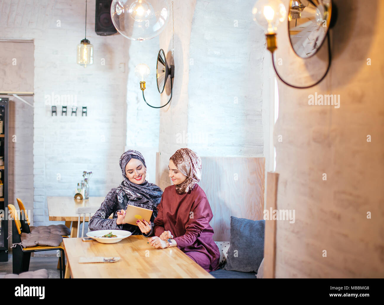 Two Muslim women in cafe, shop online using electronic tablet Stock ...