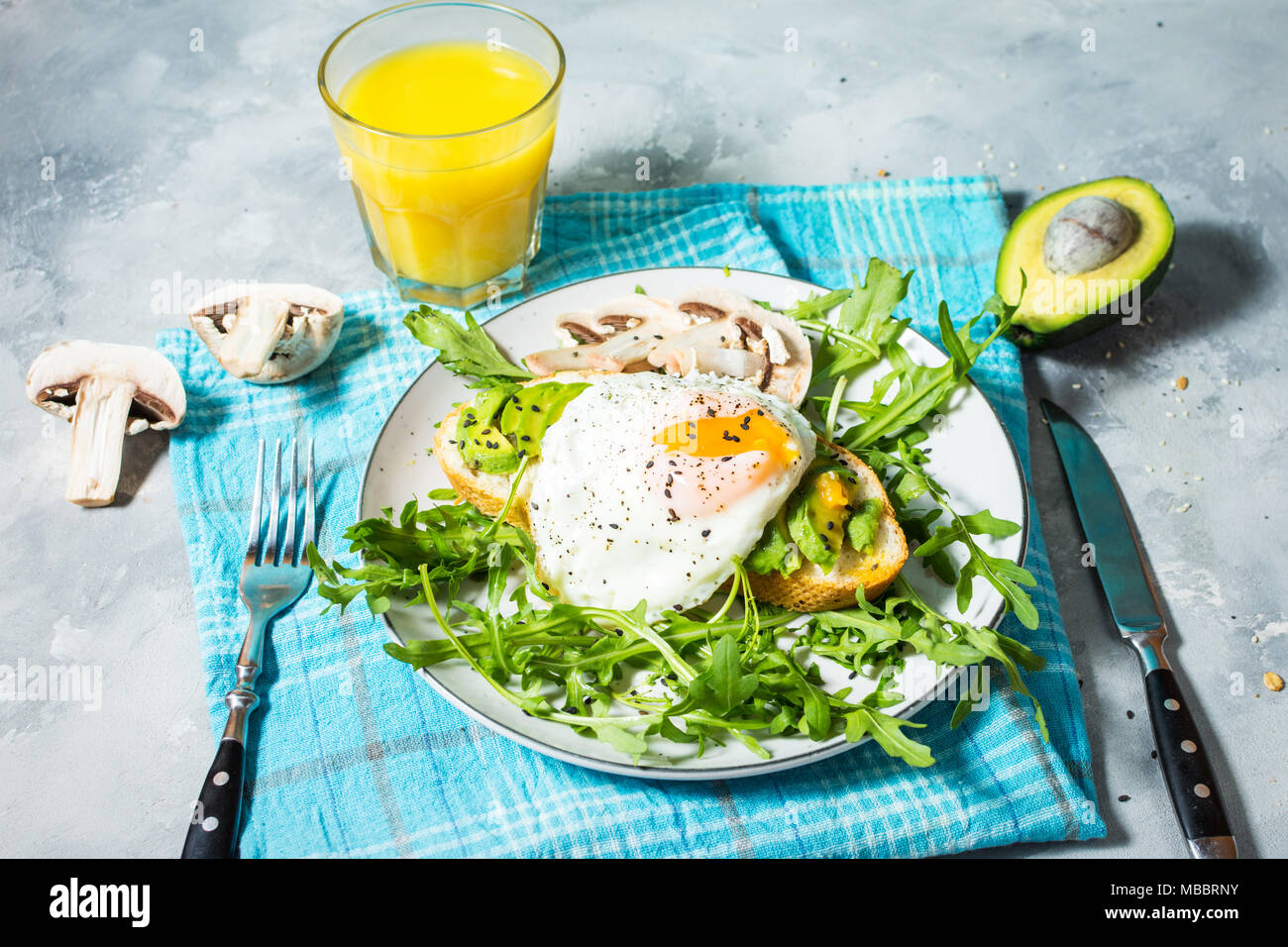 Tasty sandwich with avocado and egg, arugula on concrete background ...