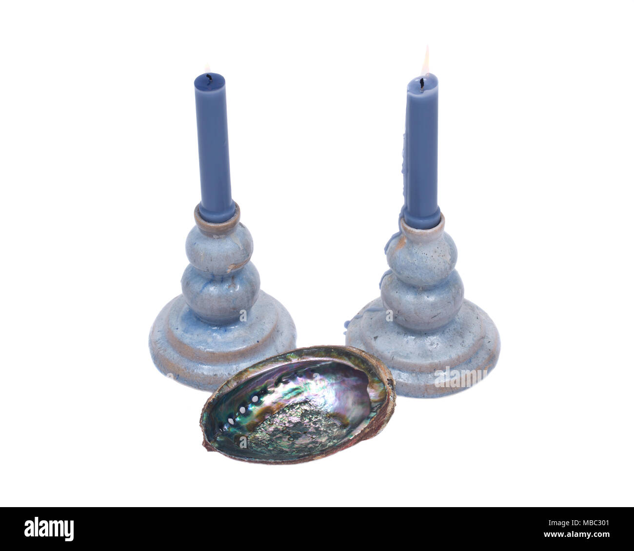 Blue clay ceramic candle holder, blue candle and polished rainbow abalone shell isolated on ...