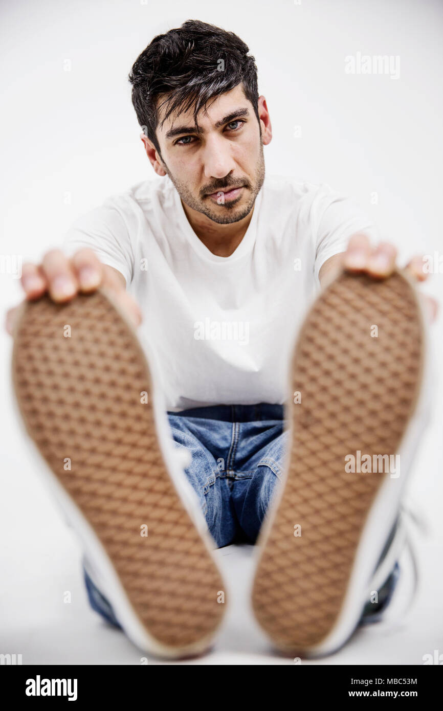 Young man touching his shoes, studio shot Stock Photo - Alamy