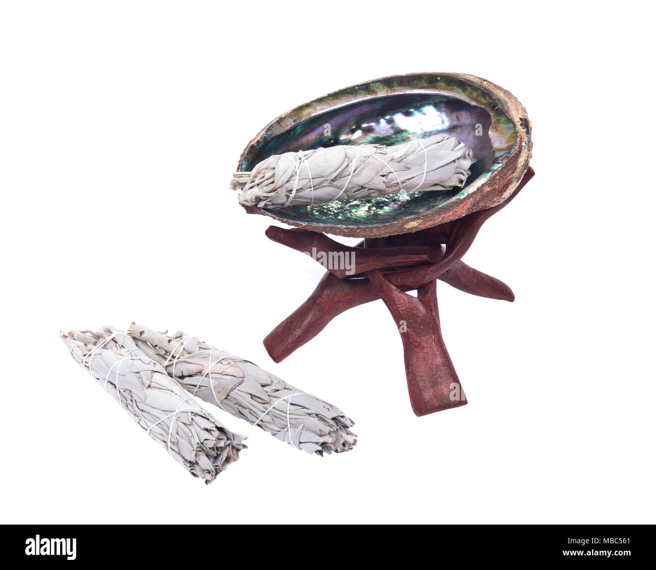 Sage smudge stick and bright polished rainbow abalone shell with wooden cobra stand isolated on ...