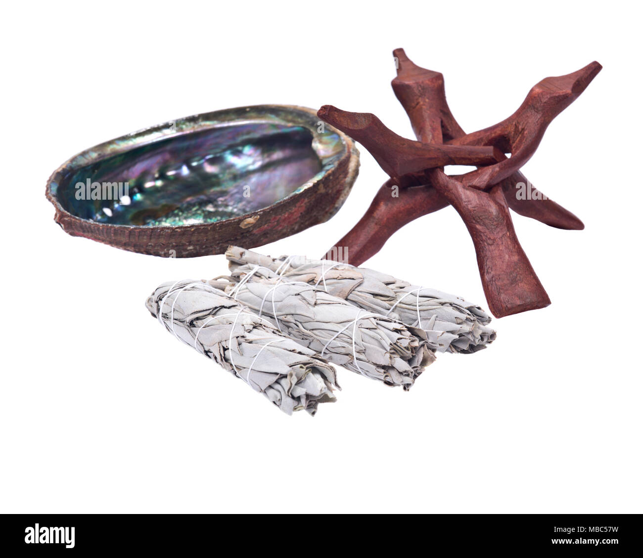 Sage smudge stick and bright polished rainbow abalone shell with wooden cobra stand isolated on ...