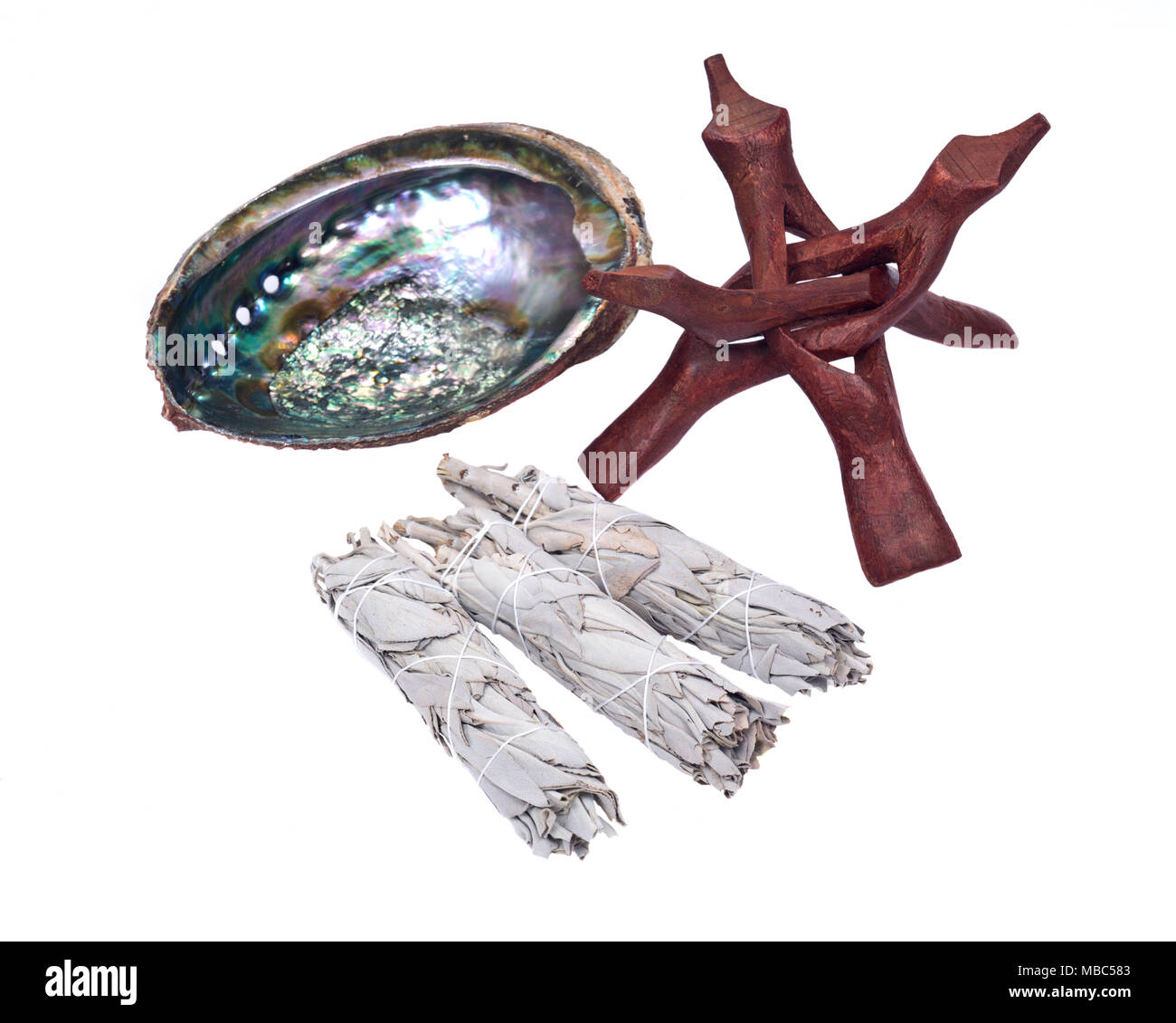 Sage smudge stick and bright polished rainbow abalone shell with wooden cobra stand isolated on ...