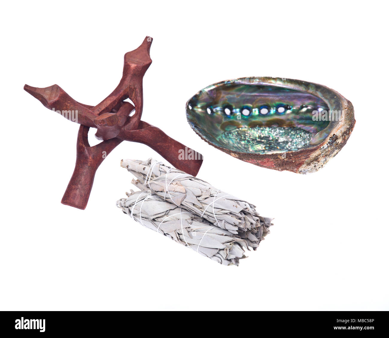 Sage smudge stick and bright polished rainbow abalone shell with wooden cobra stand isolated on ...