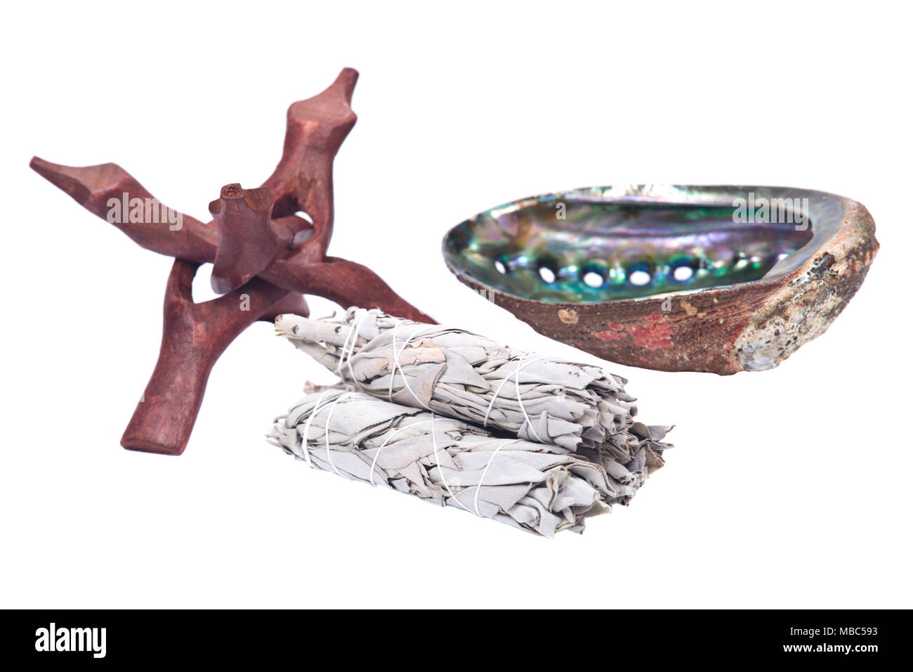 Sage smudge stick and bright polished rainbow abalone shell with wooden cobra stand isolated on ...