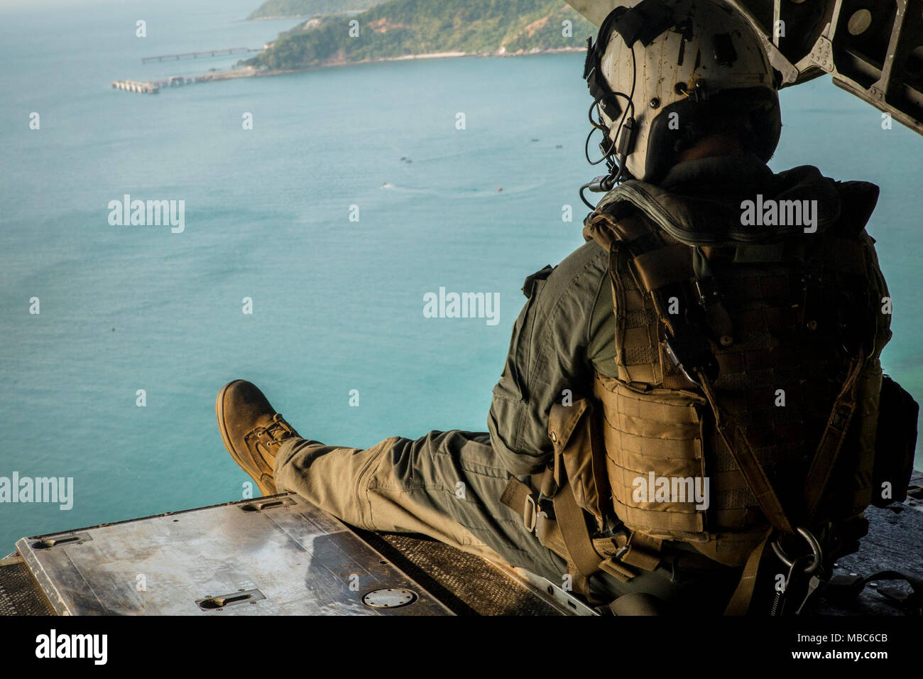 A U.S. Marine crew chief sits on the ramp of a CH-53E Super Stallion ...