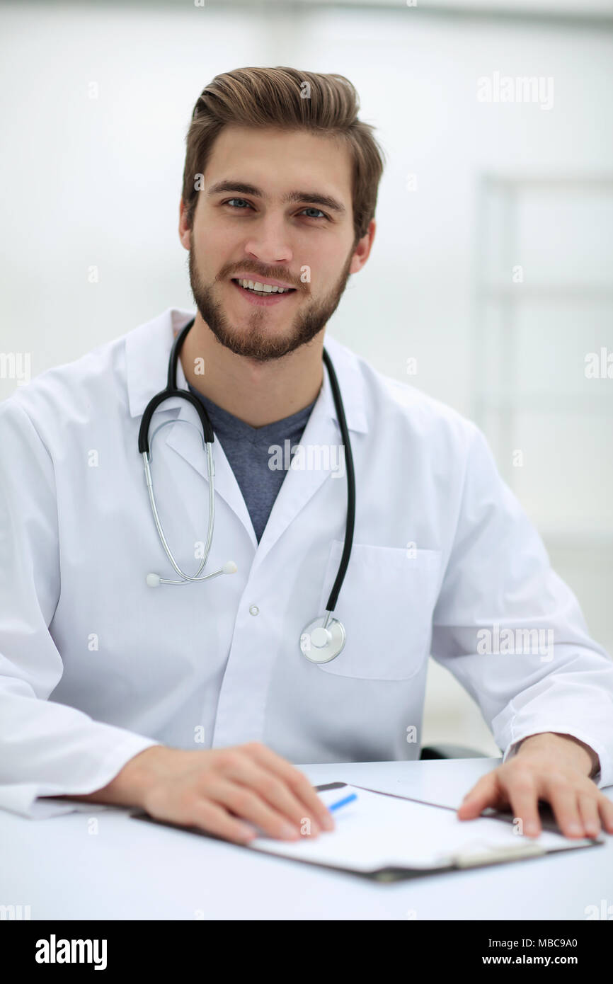 friendly doctor sitting behind a Desk Stock Photo - Alamy