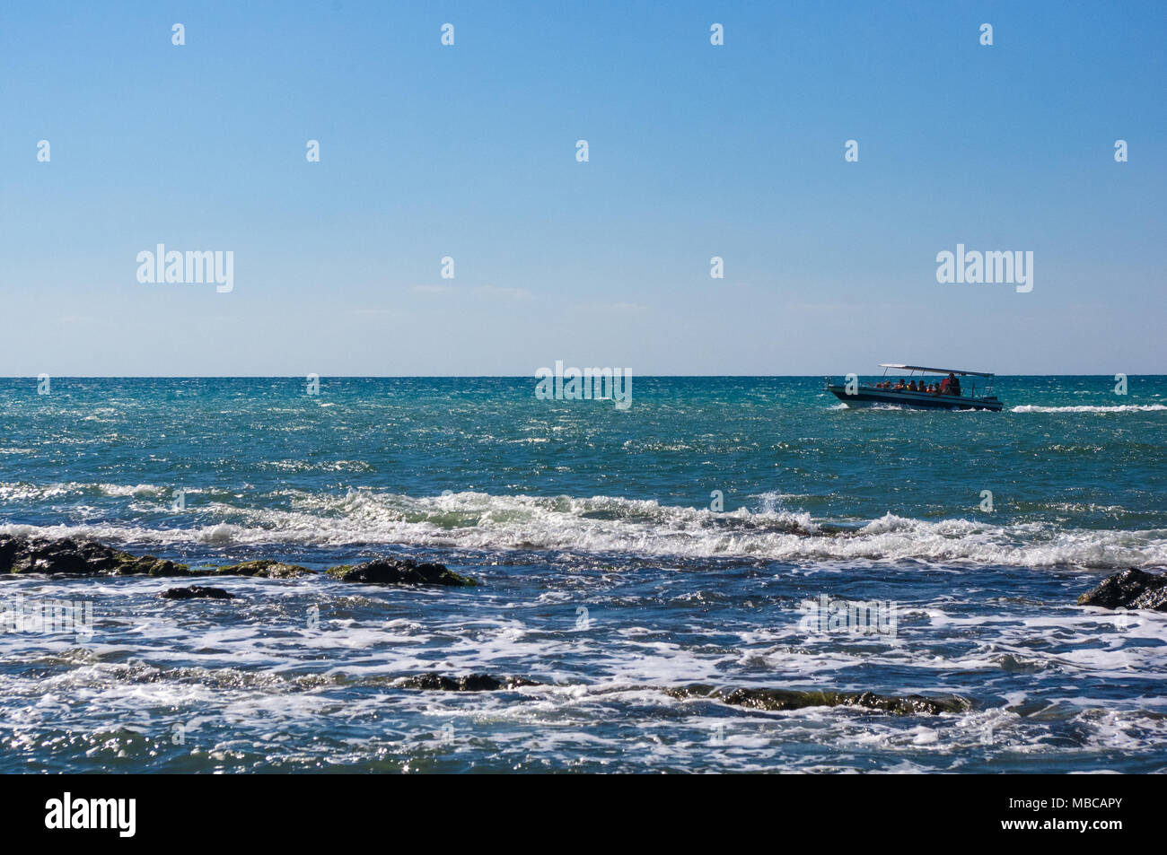 Boat in the sea, rocky sea shore with pebble beach, transparent waves ...