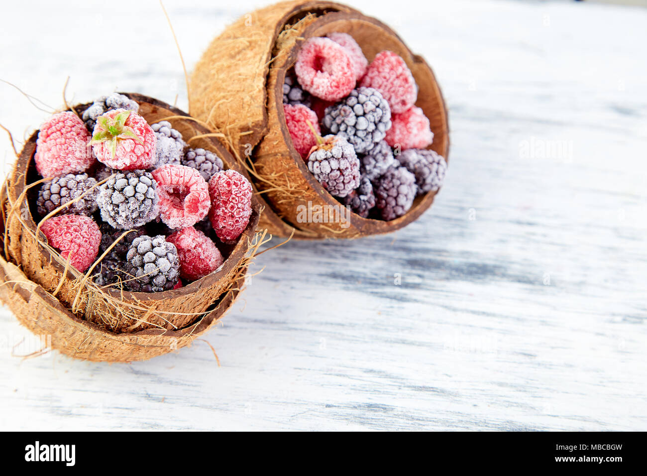 Frozen black and red raspberries in coconut bowl. Top view Stock Photo ...