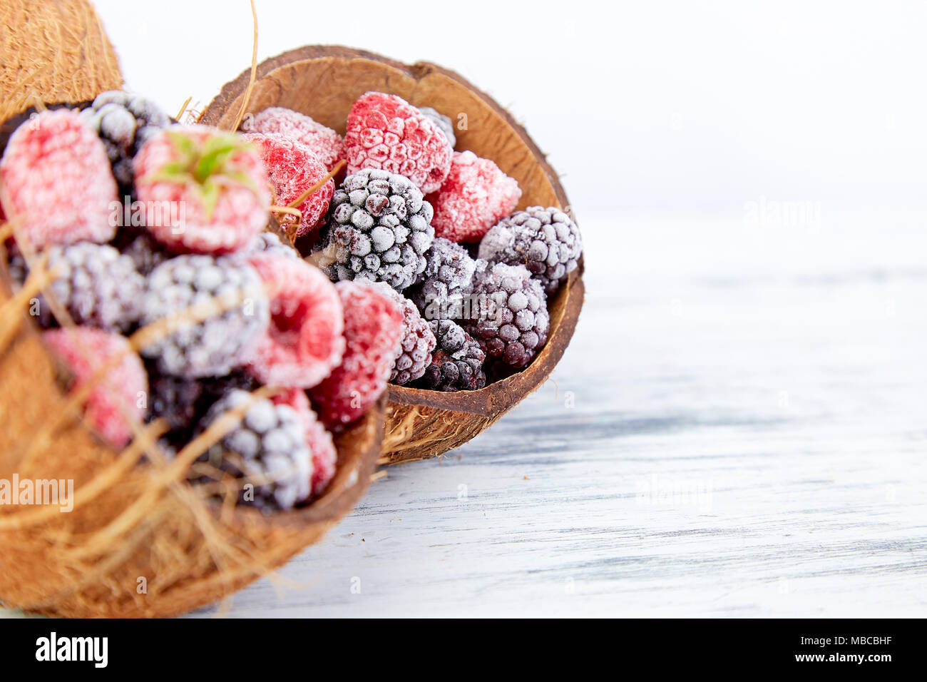 Frozen black and red raspberries in coconut bowl Stock Photo - Alamy