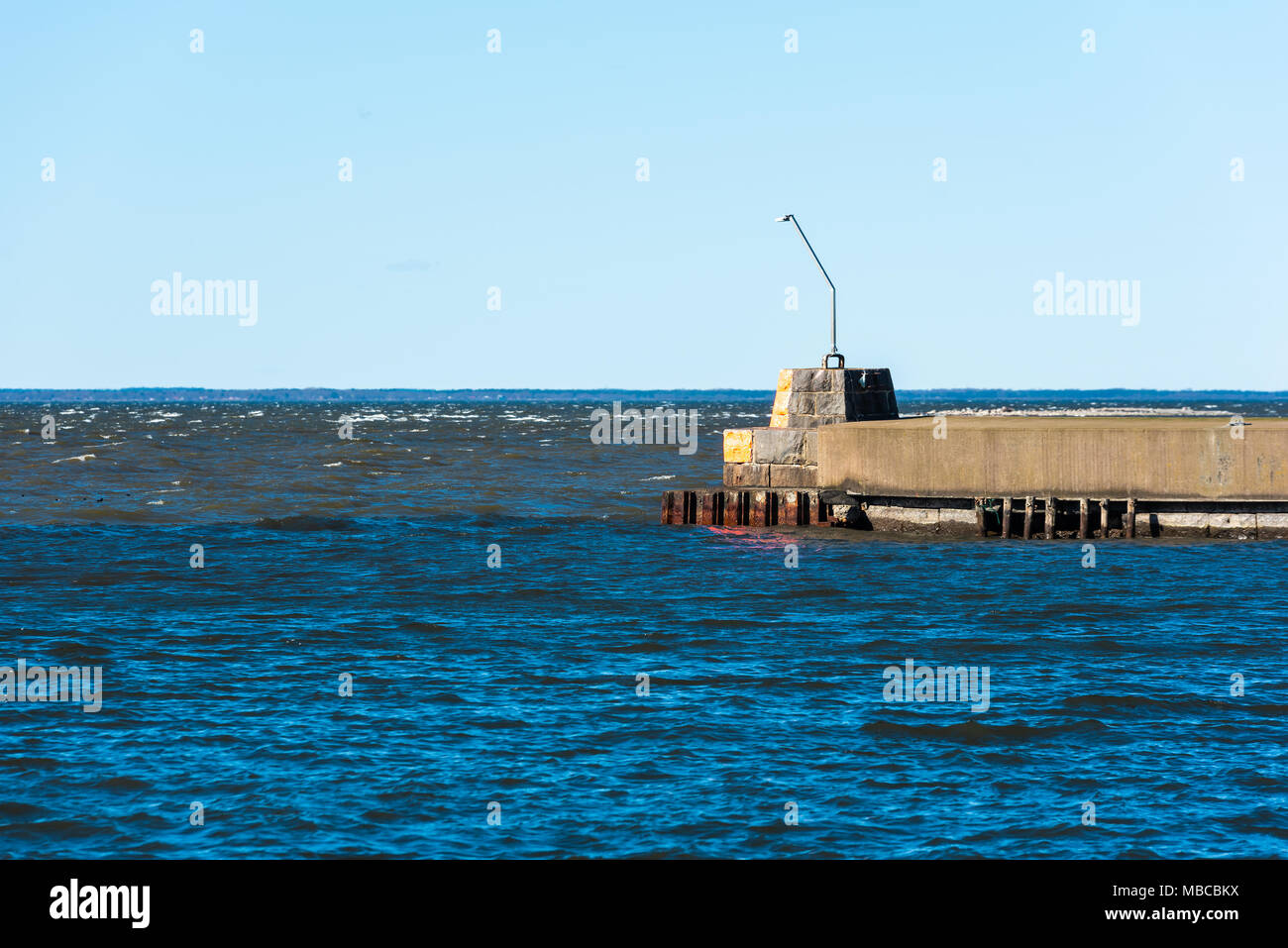 Concrete pier end with streetlight or lamp on a sunny and windy day ...
