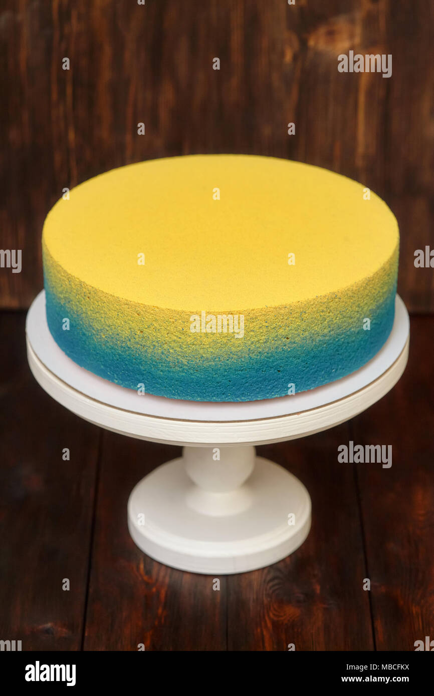 Blue and yellow cake on stand over wooden background, closeup Stock ...