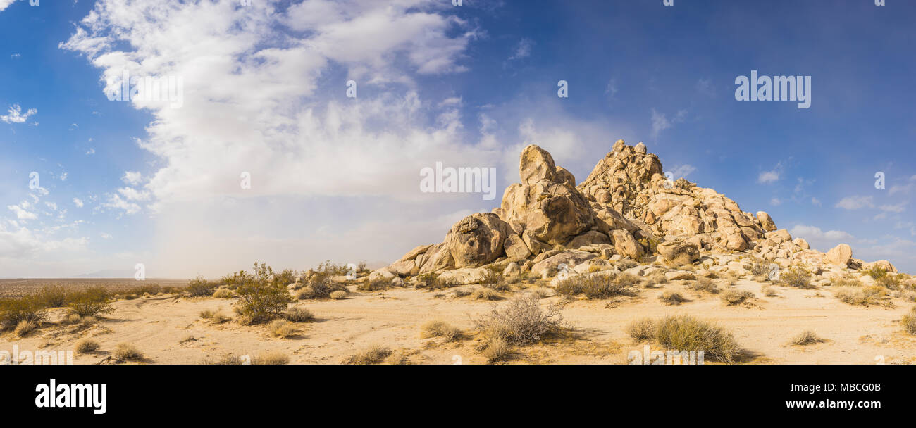 Sand desert holds pile of rock boulders forming a hill in the midst of ...