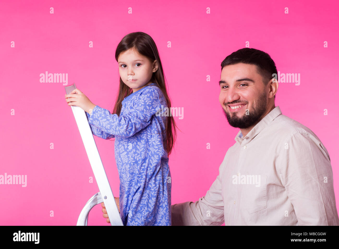 Father with his baby daughter smiling over pink background Stock Photo ...