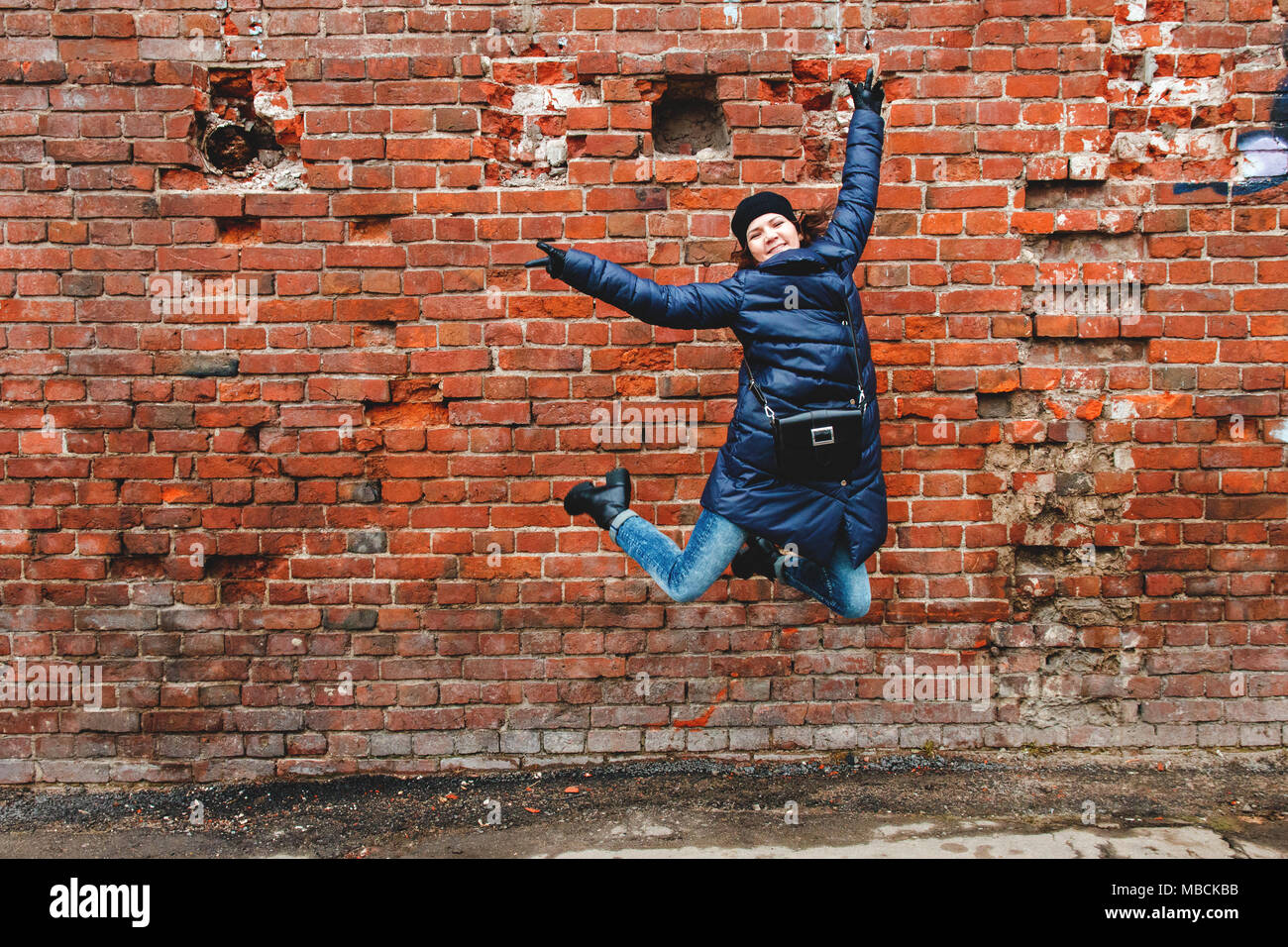 smiling girl was photographed in a jump on a brick wall background ...