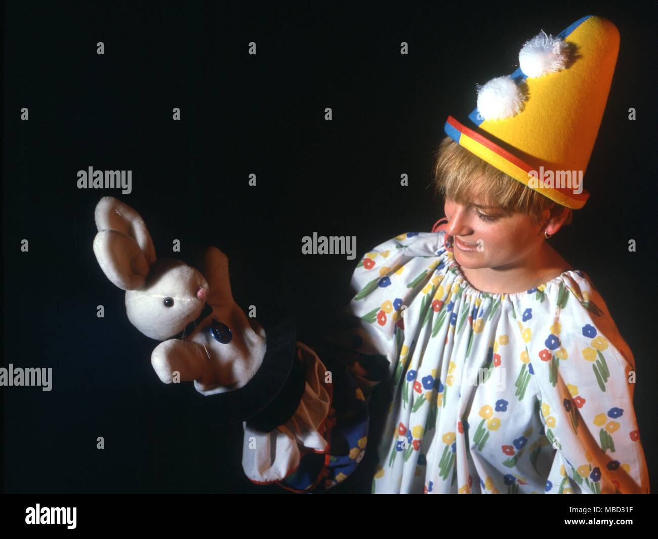 Stage Magic. The clown-magician takes a toy rabbit from a hat and ...