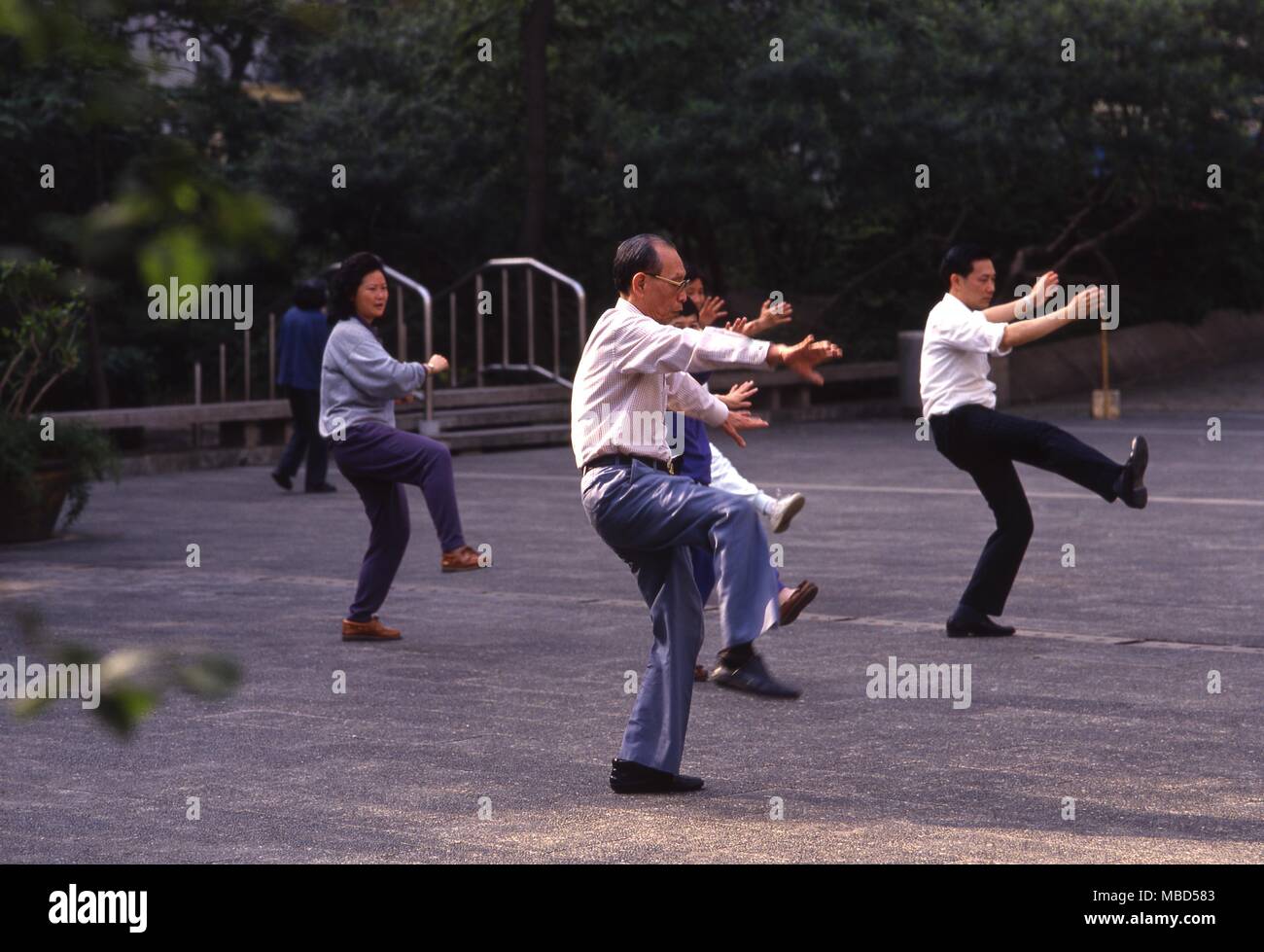Chinese master of Tai Chi with his students in a park in Hong Kong ...