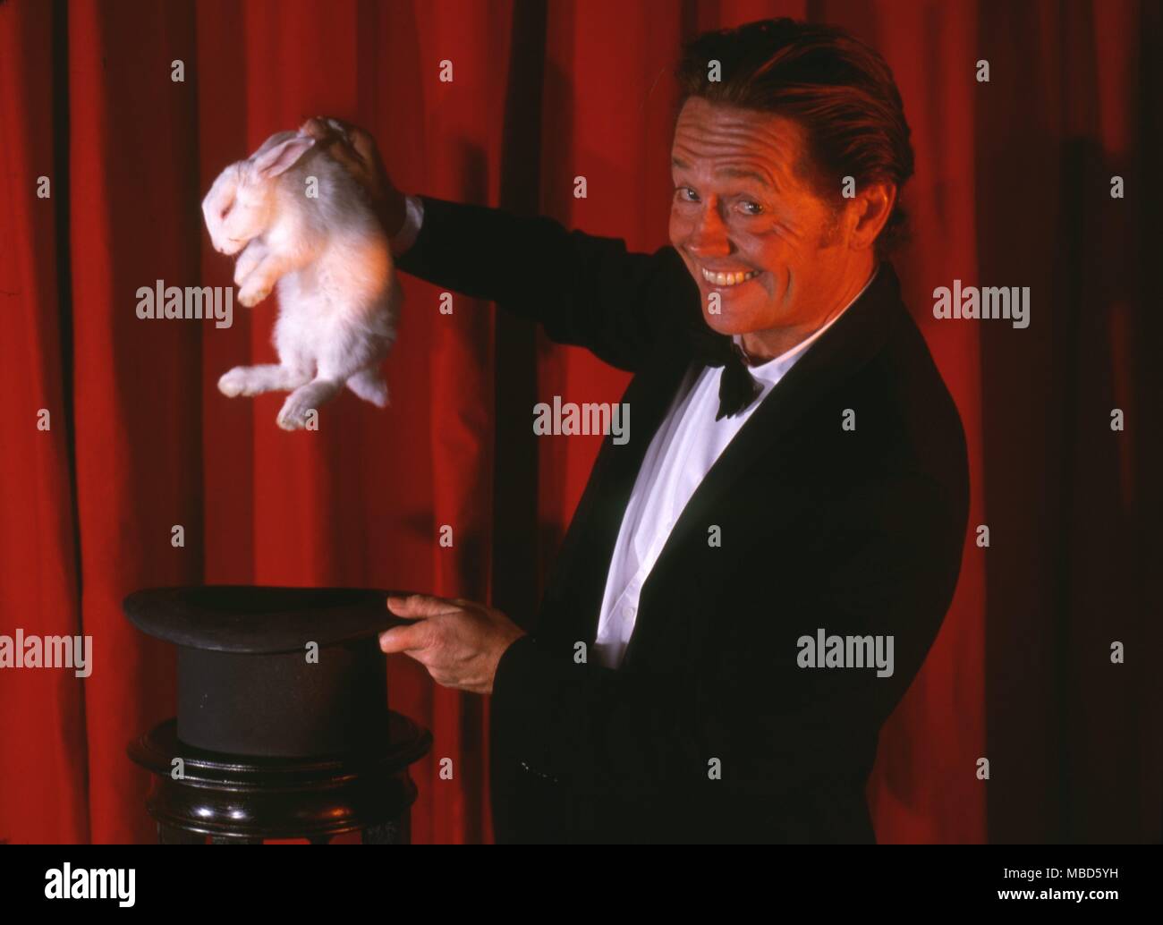 Stage magic - Rabbit from top hat The magician lifting a white rabbit ...