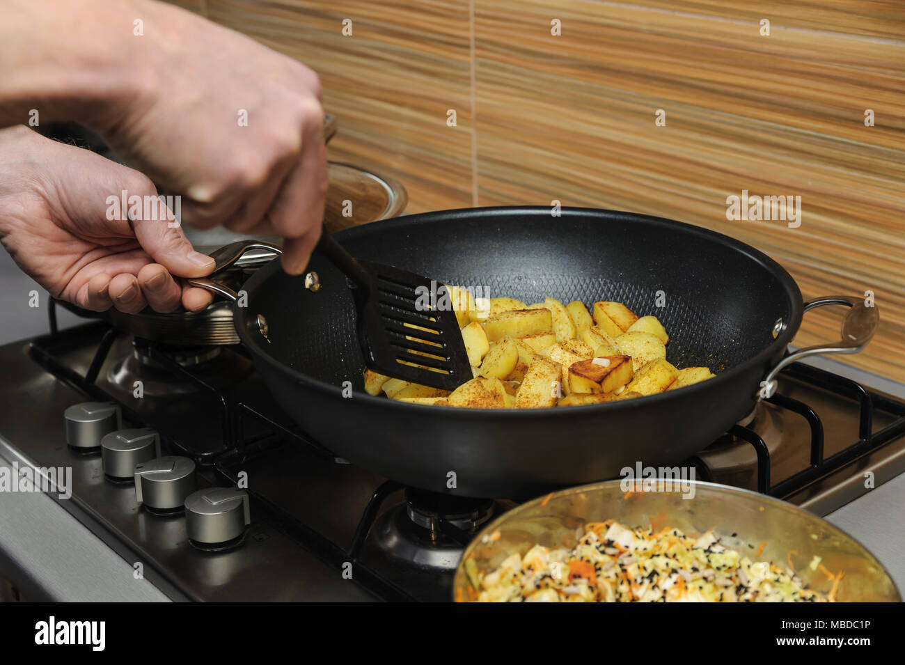 Cooking at home kitchen. Man fries potatoes in a frying pan Stock Photo ...