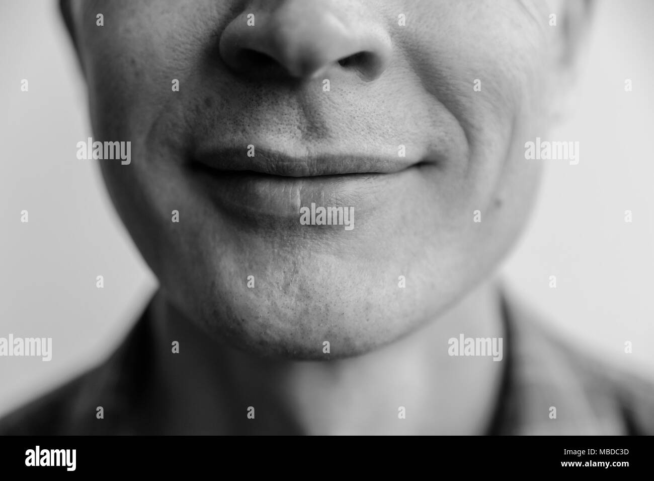 Easy smile closeup. The lower part of the face of a man. Black and ...
