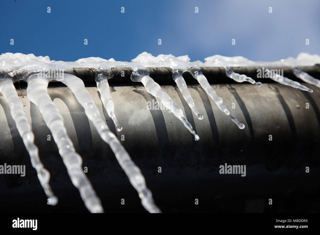 Icicle in the eaves spout with a blue sky background Stock Photo - Alamy