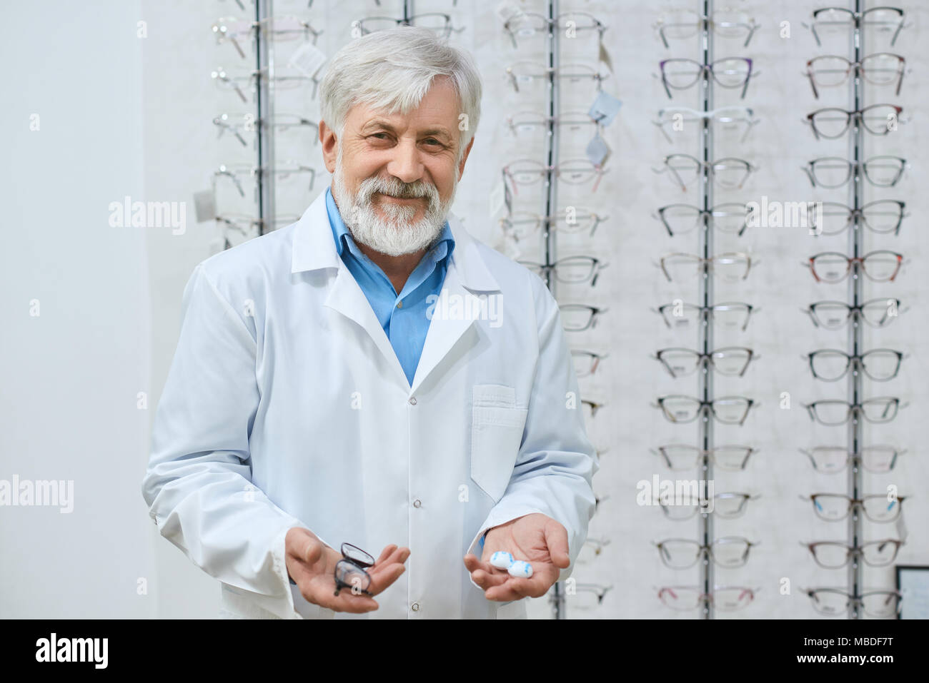 Expirienced old oculist helping to choose eyeglasses in ophthalmologic ...