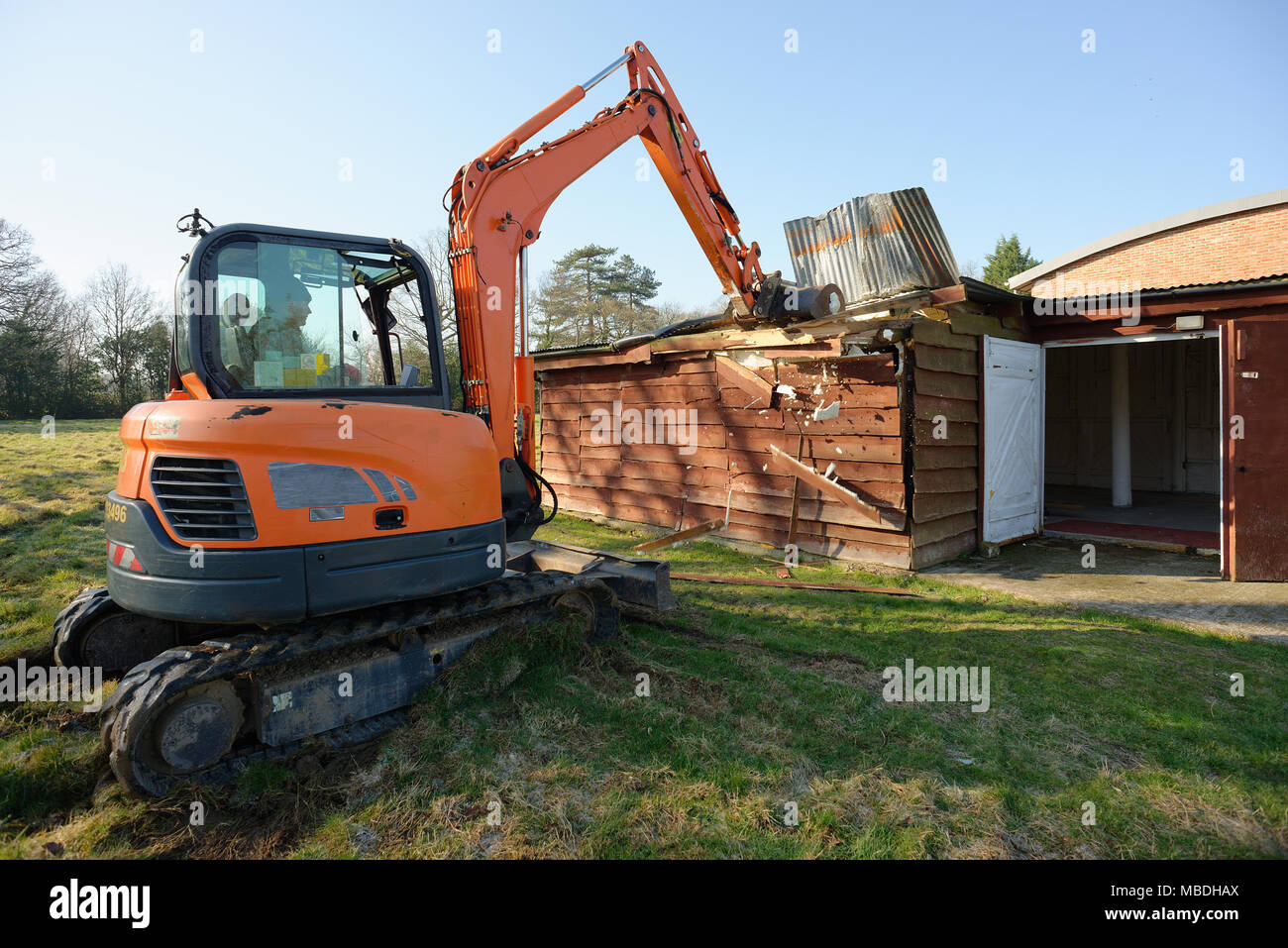 A large digger being used to demolish an old wooden barn Stock Photo ...
