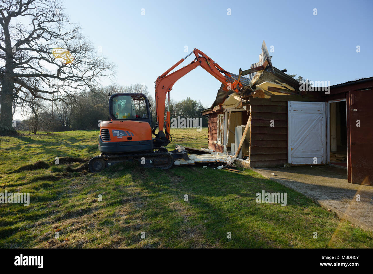 A large digger being used to demolish an old wooden barn Stock Photo ...