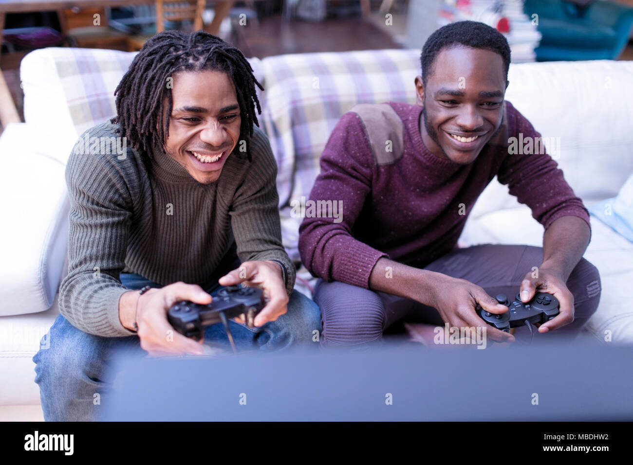 Smiling brothers playing video game on sofa Stock Photo - Alamy