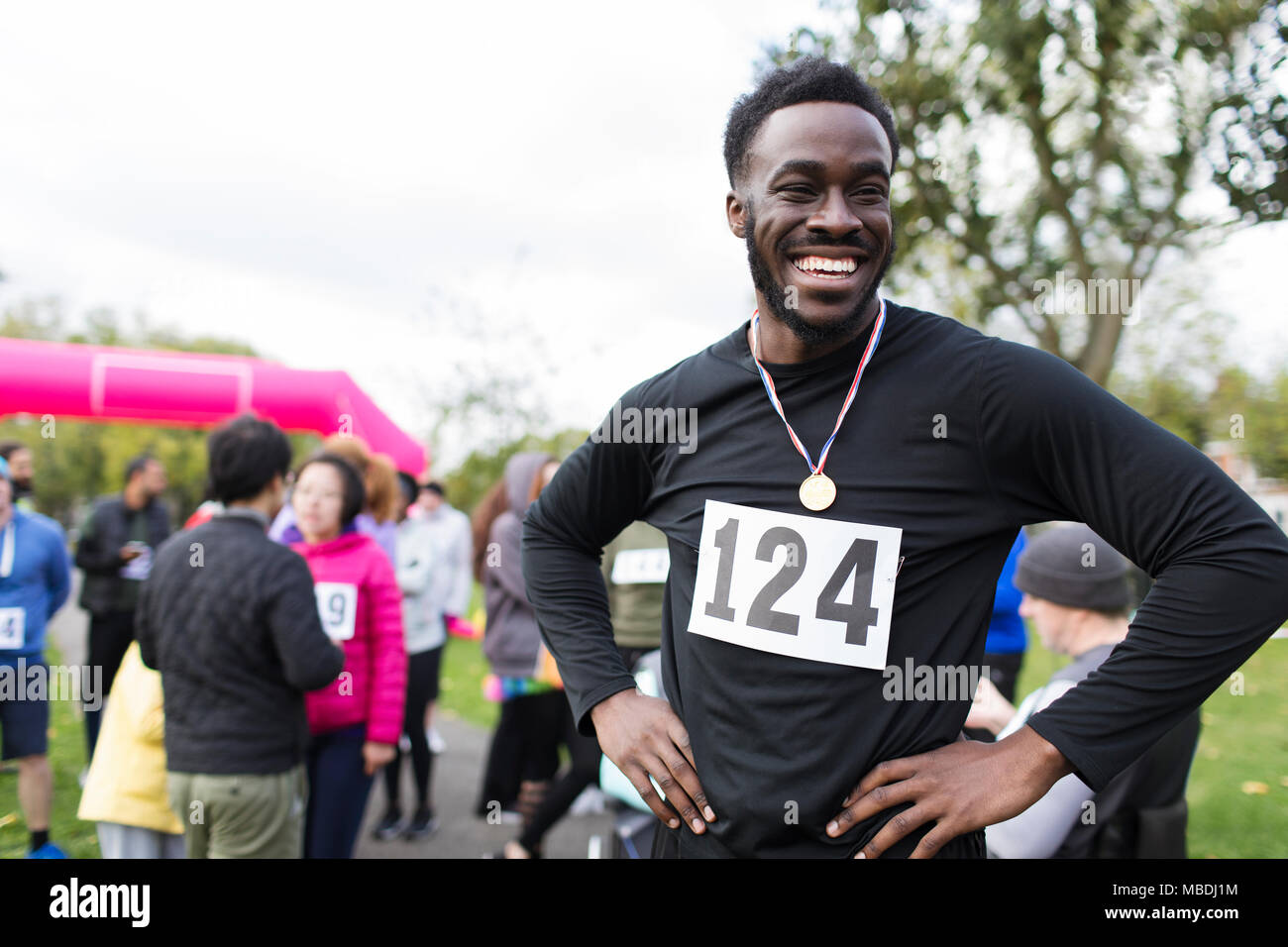 Portrait happy, confident male runner wearing medal at charity run in ...