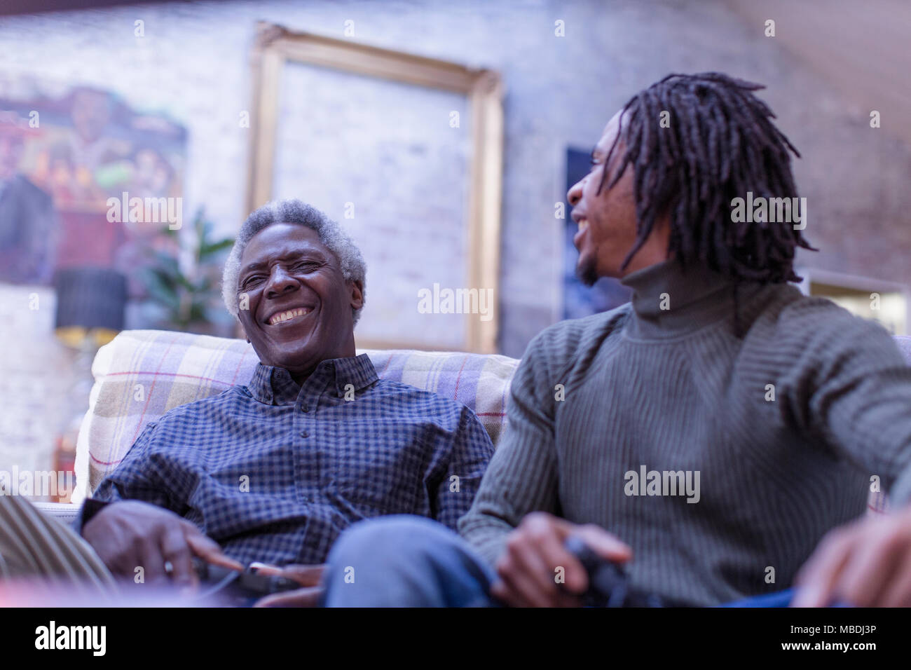 Grandfather and grandson laughing, playing video game on sofa Stock ...