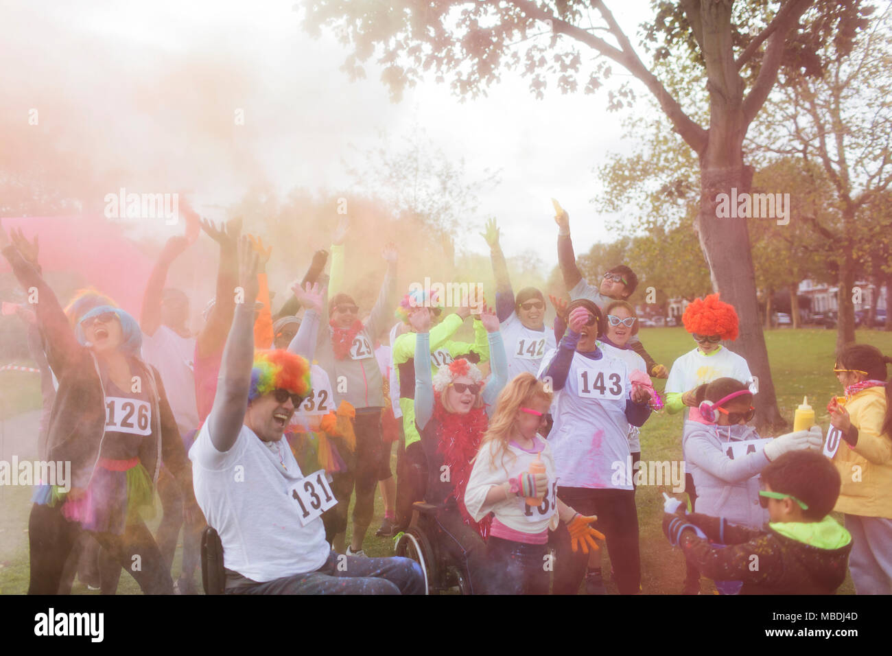 Playful runners throwing holi powder at charity run in park Stock Photo ...