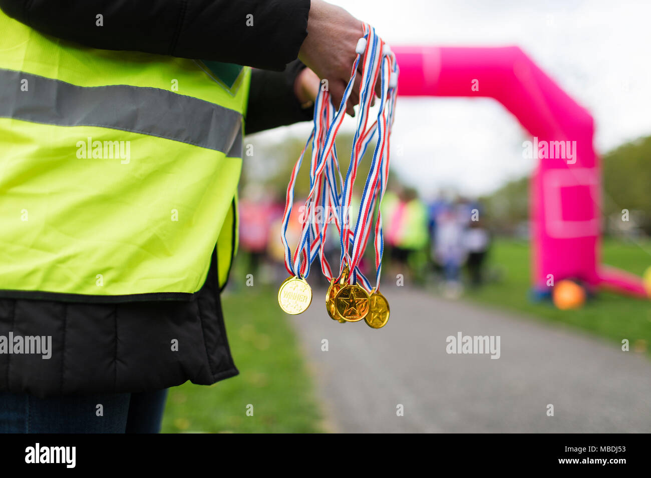 Volunteer holding medals at charity run Stock Photo - Alamy