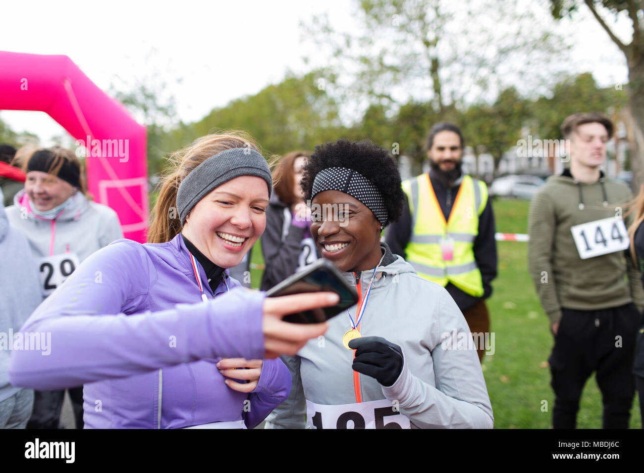 Female runner friends using smart phone at charity run in park Stock ...