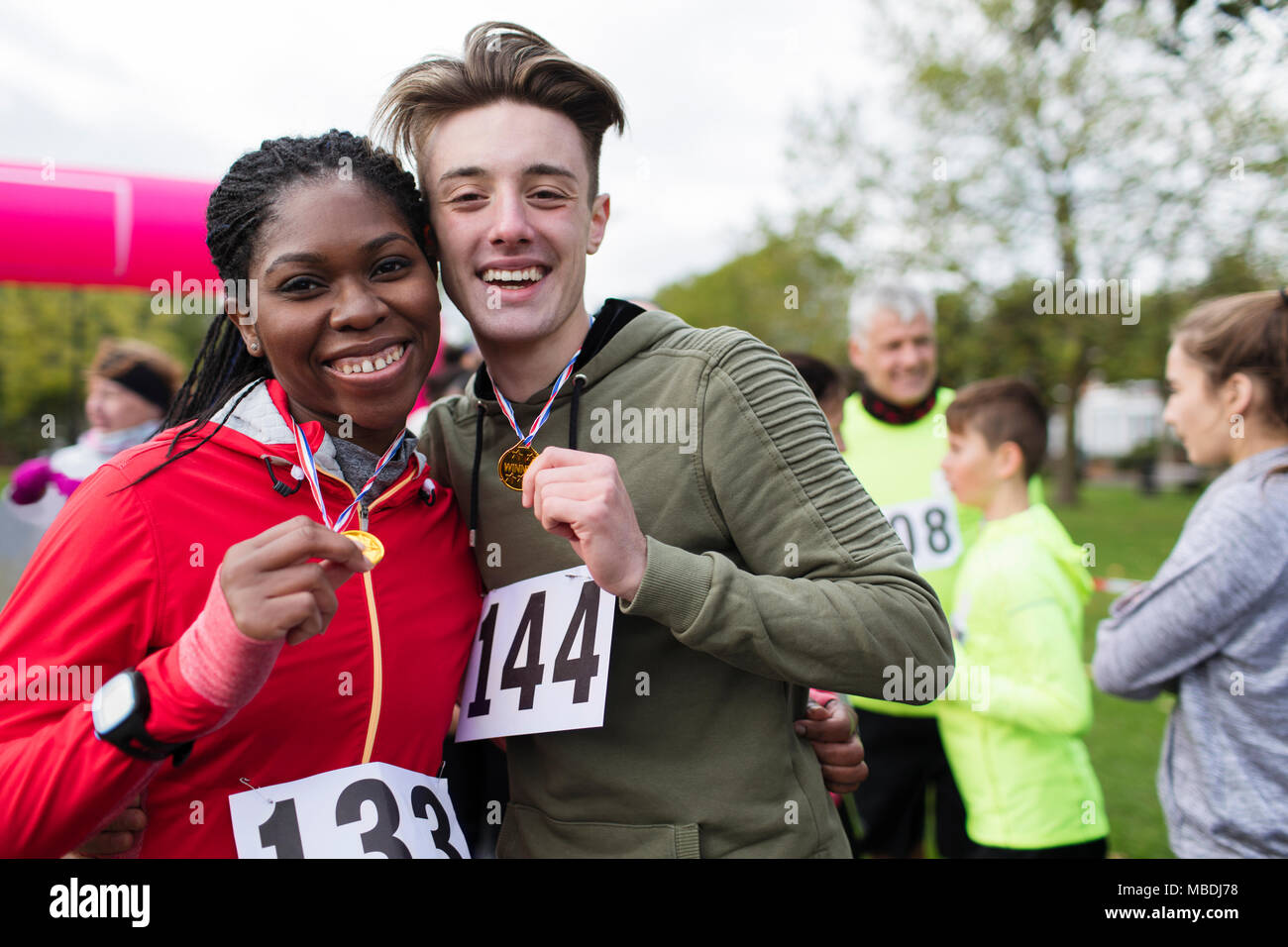 Portrait smiling, confident couple runners showing medals at charity ...