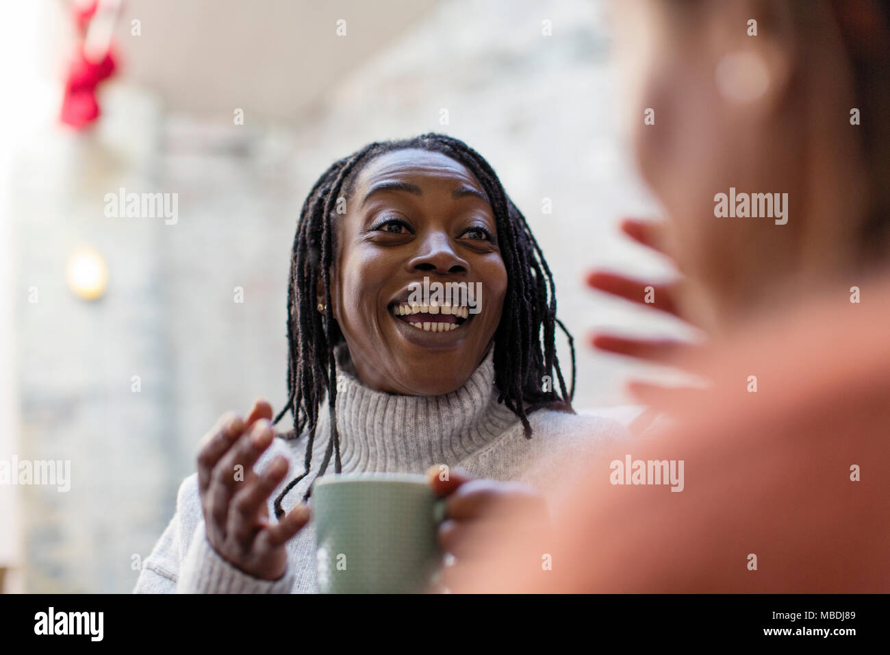 Enthusiastic woman drinking coffee, talking with friend Stock Photo - Alamy