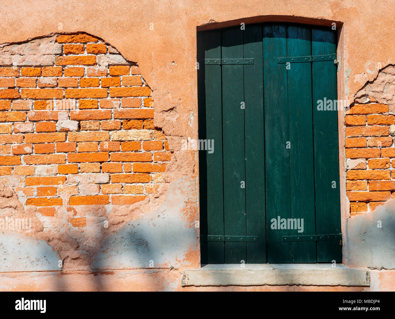 Window with green shutters on red brick wall of houses. Italy, Venice ...