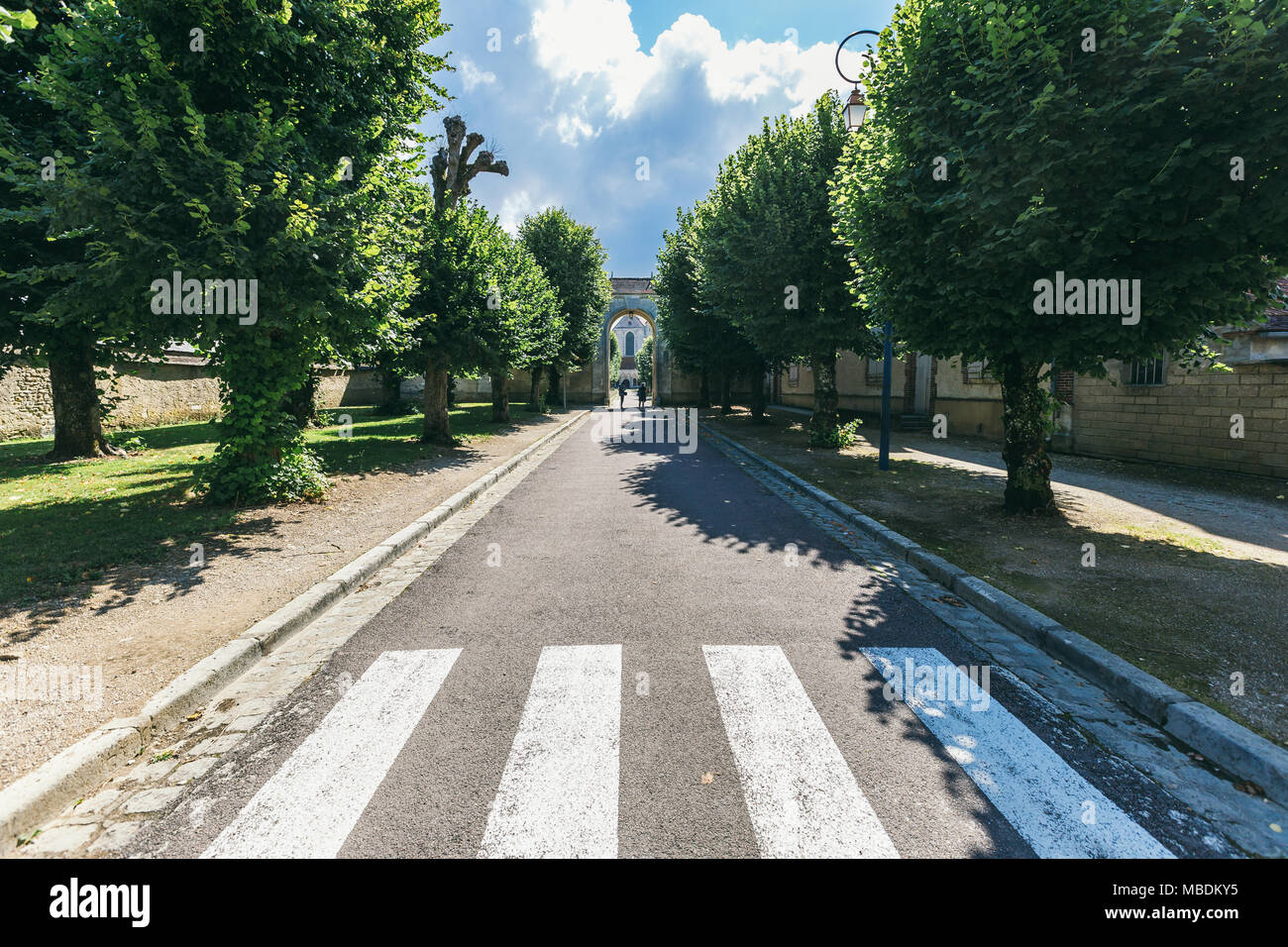 pedestrian crossing on a narrow street in a small town. In the distance ...