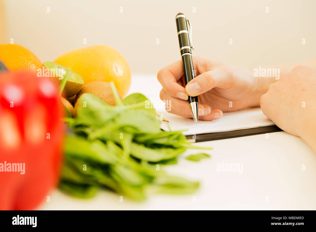 Nutritionist woman writing diet plan on table full of fruits and ...