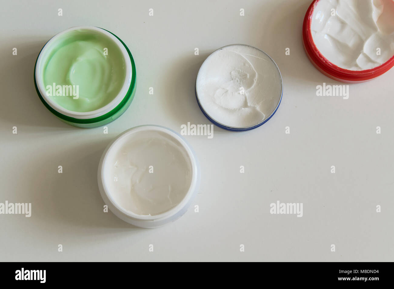 Top view of different opened body/face creams on white background ...