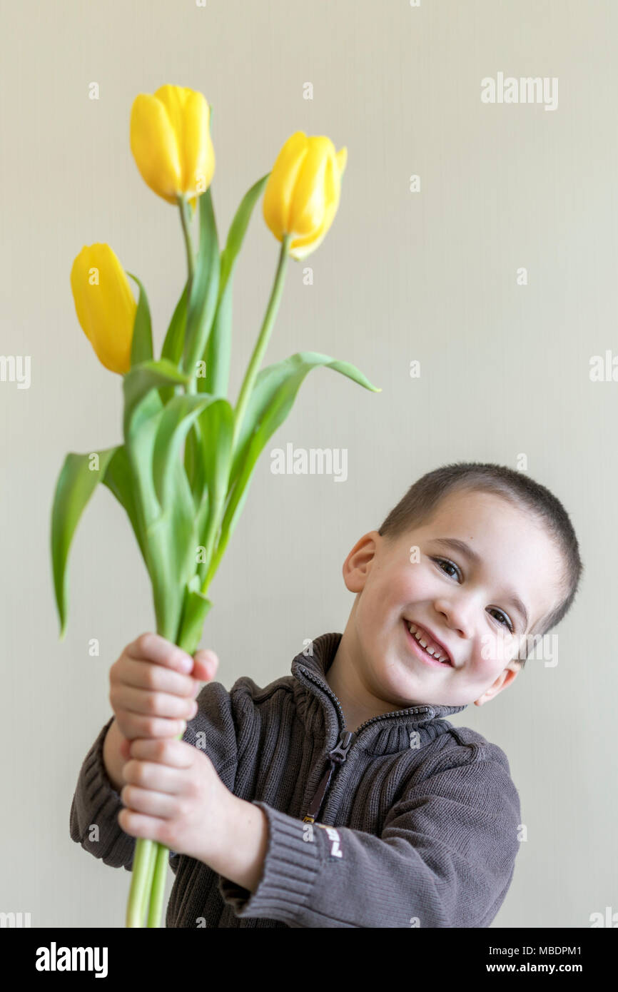 Boy hiding flower on his hands. Light background. European appearance ...