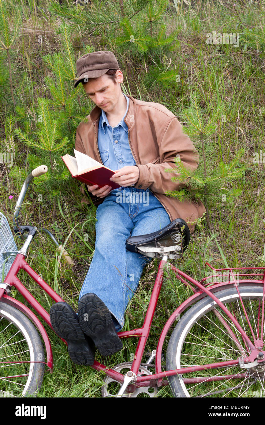 Man reads book, sitting on a mountain slope Stock Photo - Alamy