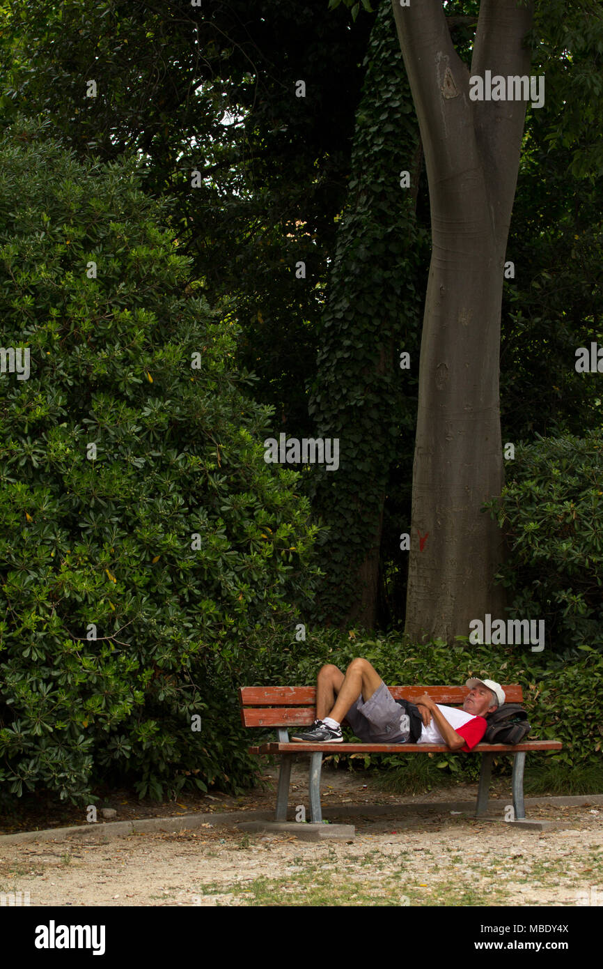 A man asleep on a park bench in a park in Venice, Italy Stock Photo - Alamy