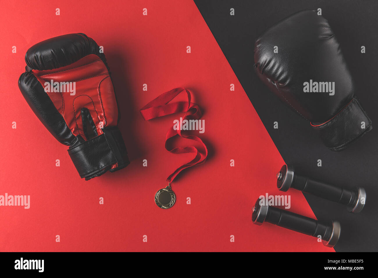 top view of boxing gloves with medal and dumbbells on red and black ...