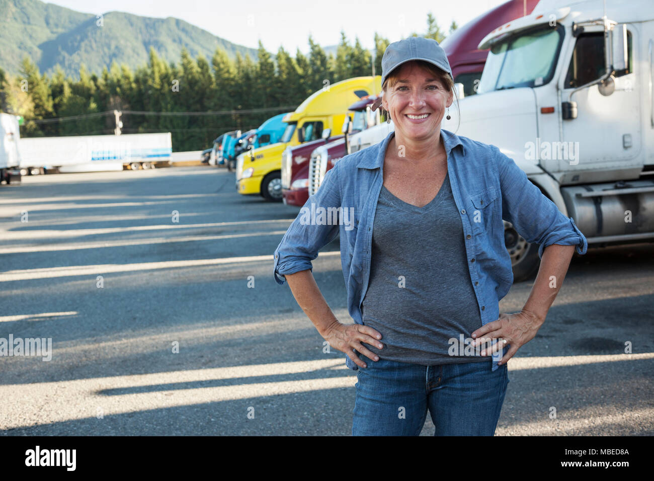 A caucasian woman truck driver near her truck parked in a parking lot ...
