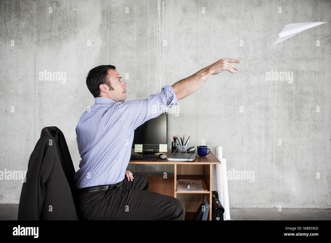Caucasian businessman throwing a paper airplane while sitting at his ...