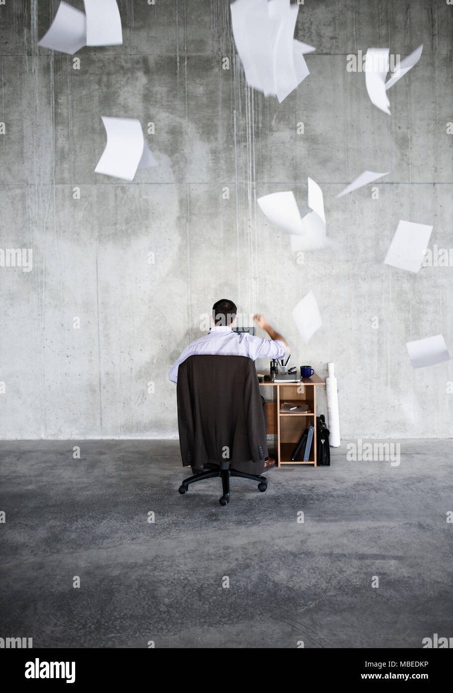 Caucasian businessman throwing papers in air while sitting at his desk ...
