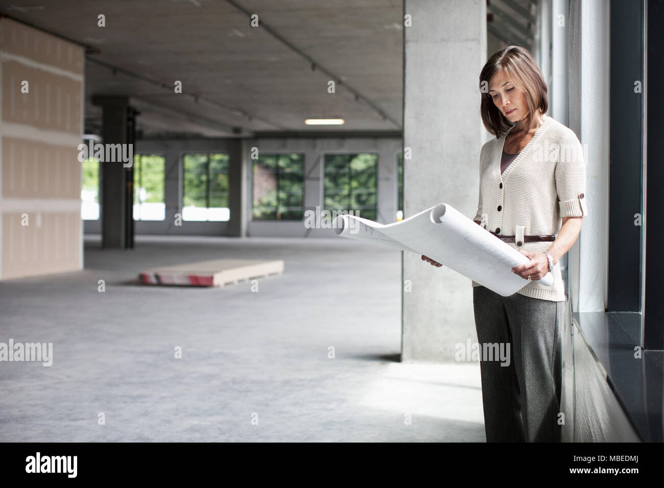 Caucasian businesswoman going over plans for a new office in a large ...